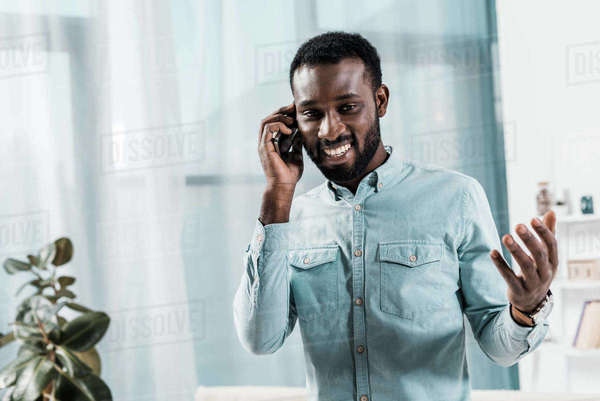 African American man talking on smartphone in living room - Stock Photo ...