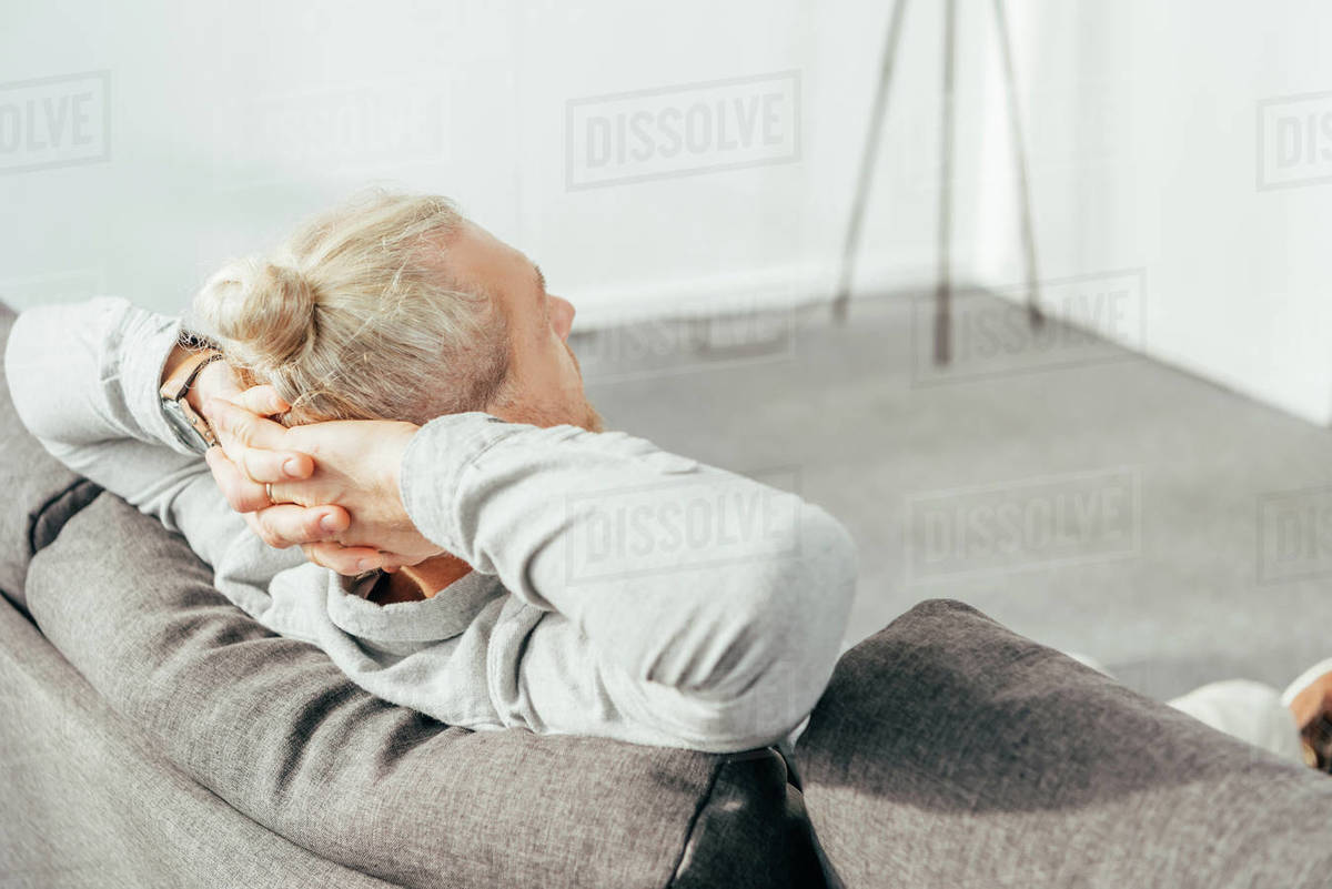 Back view of man resting with hands behind head on couch - Royalty-free ...