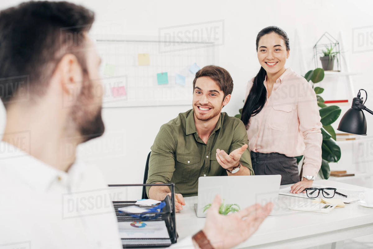 Young colleagues talking with coworker in modern office - Stock Photo ...
