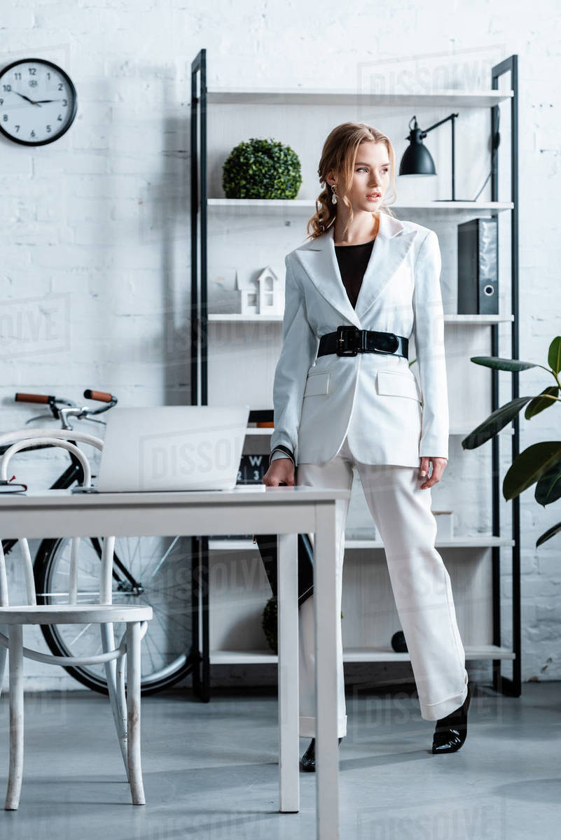 Stylish businesswoman in white formal wear in modern office interior ...
