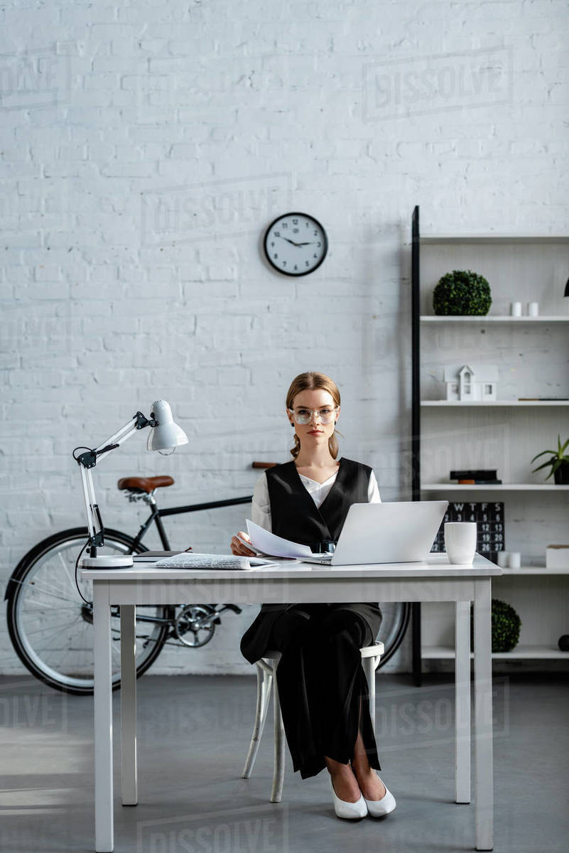 Businesswoman in formal wear sitting at computer desk with documents at ...