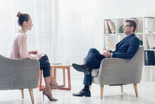 Side view of businessman giving interview to attractive journalist in ...