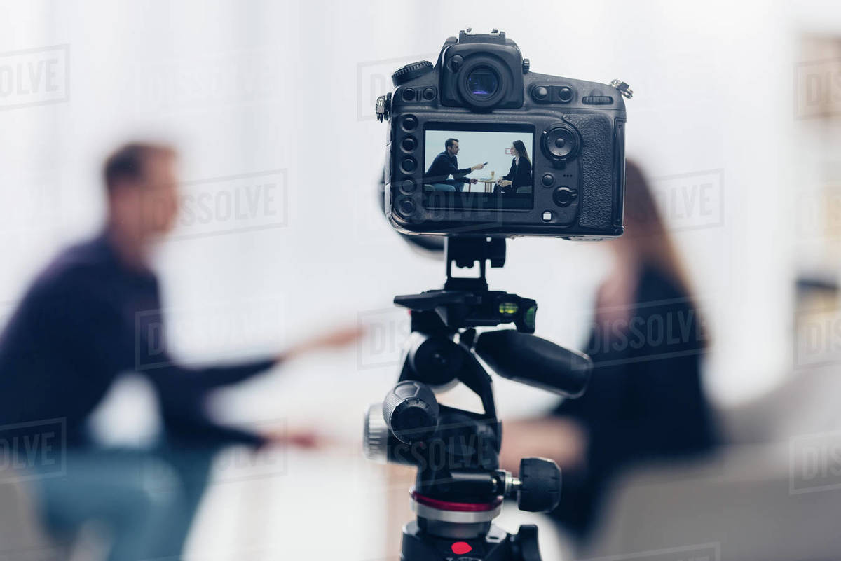 Businesswoman in suit giving interview to journalist in office, camera ...