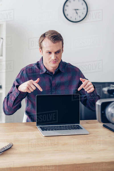 Handsome male video blogger recording vlog and pointing on laptop with ...