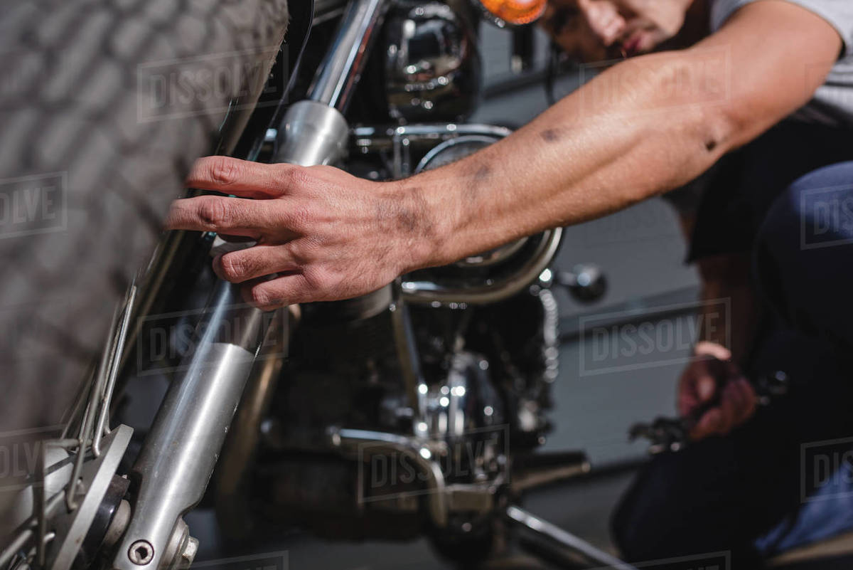 Closeup of mechanic fixing motorbike front wheel in garage - Stock ...