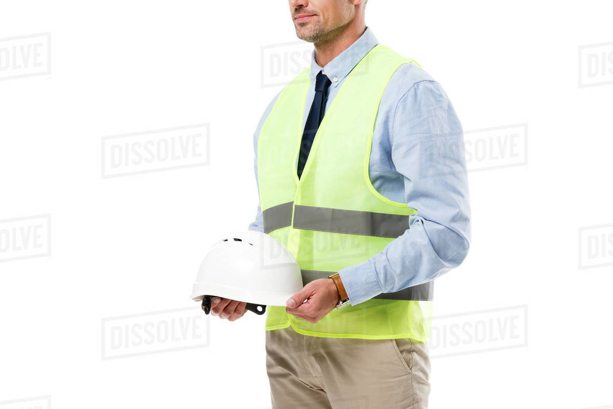 Cropped view of engineer in safety vest holding helmet isolated on ...