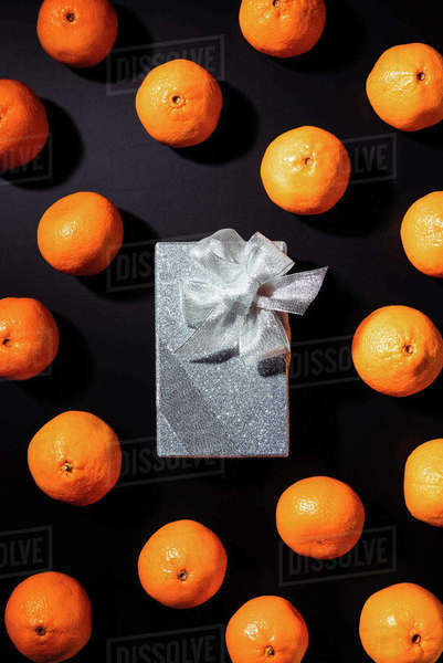 Top view of fresh tangerines and silver gift box on black background ...