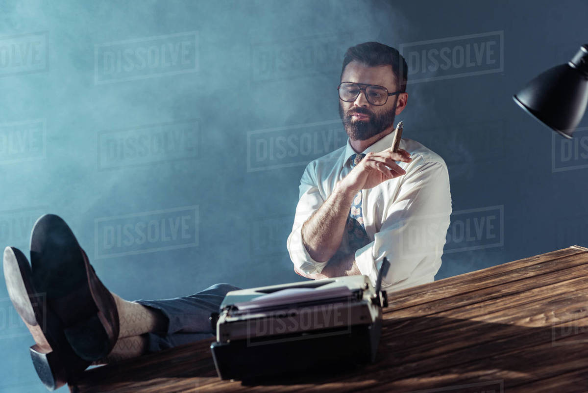 Handsome man smoking and sitting on chair near table - Stock Photo ...