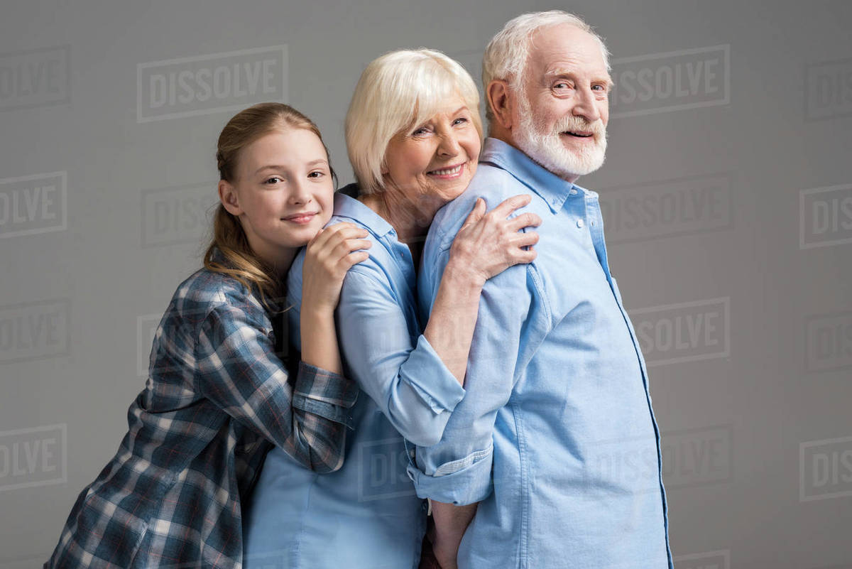 Happy family hugging and looking at camera isolated on grey in studio ...