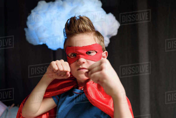 Boy in red superhero costume with fighting gesture looking at camera ...