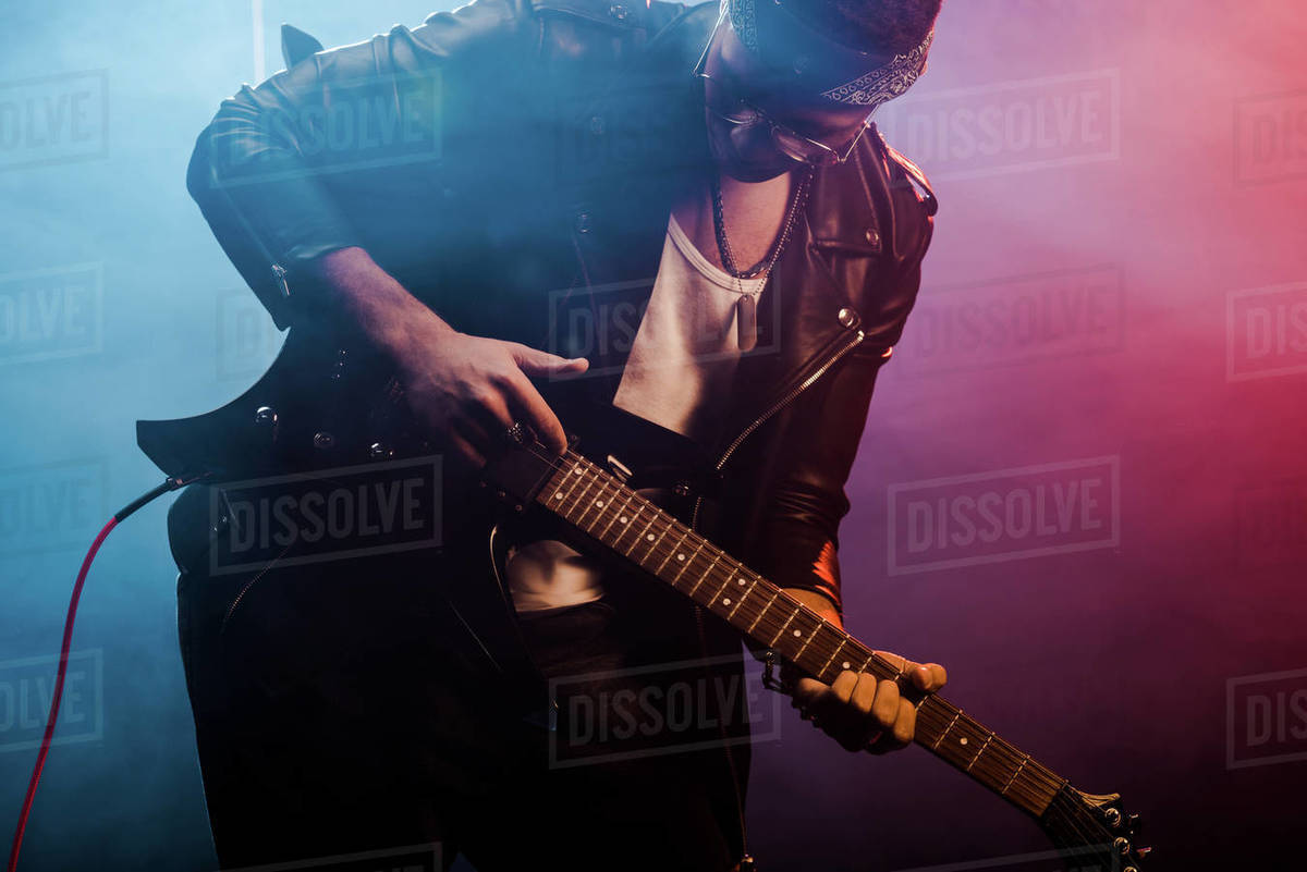 Young male rocker in leather jacket performing on electric guitar on ...