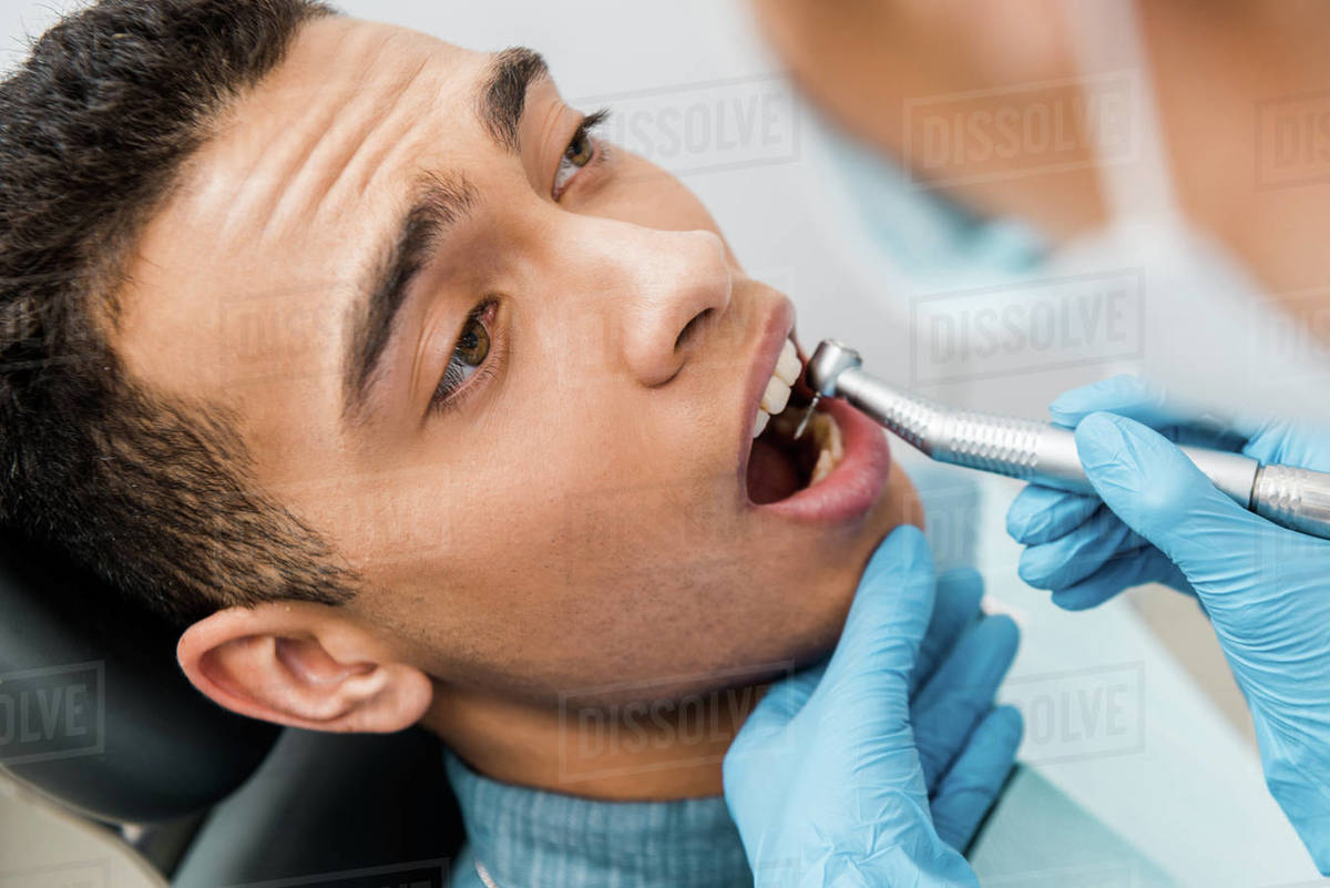 Close up of dentist hands drilling teeth of african american patient ...