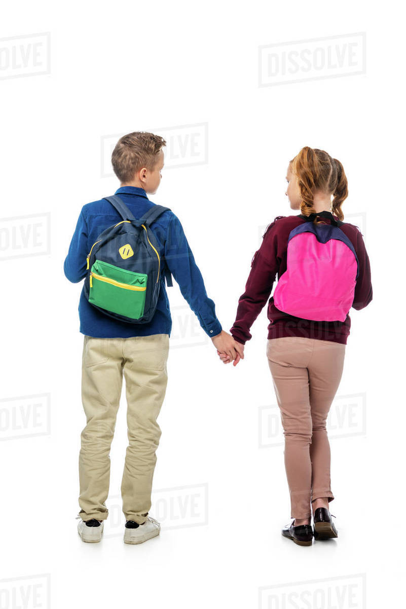 Back view of children holding hands with multicolored backpacks ...
