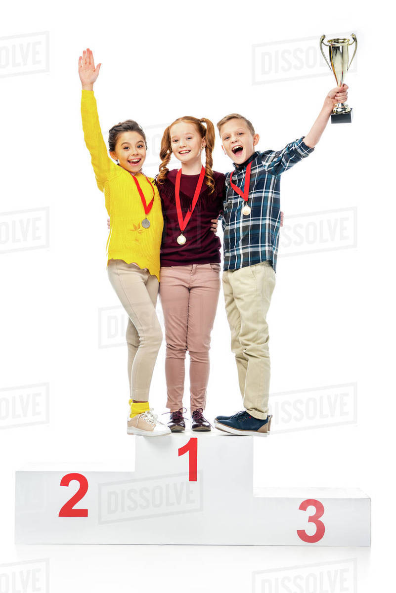 Happy kids with medals and trophy cup standing on winner pedestal ...