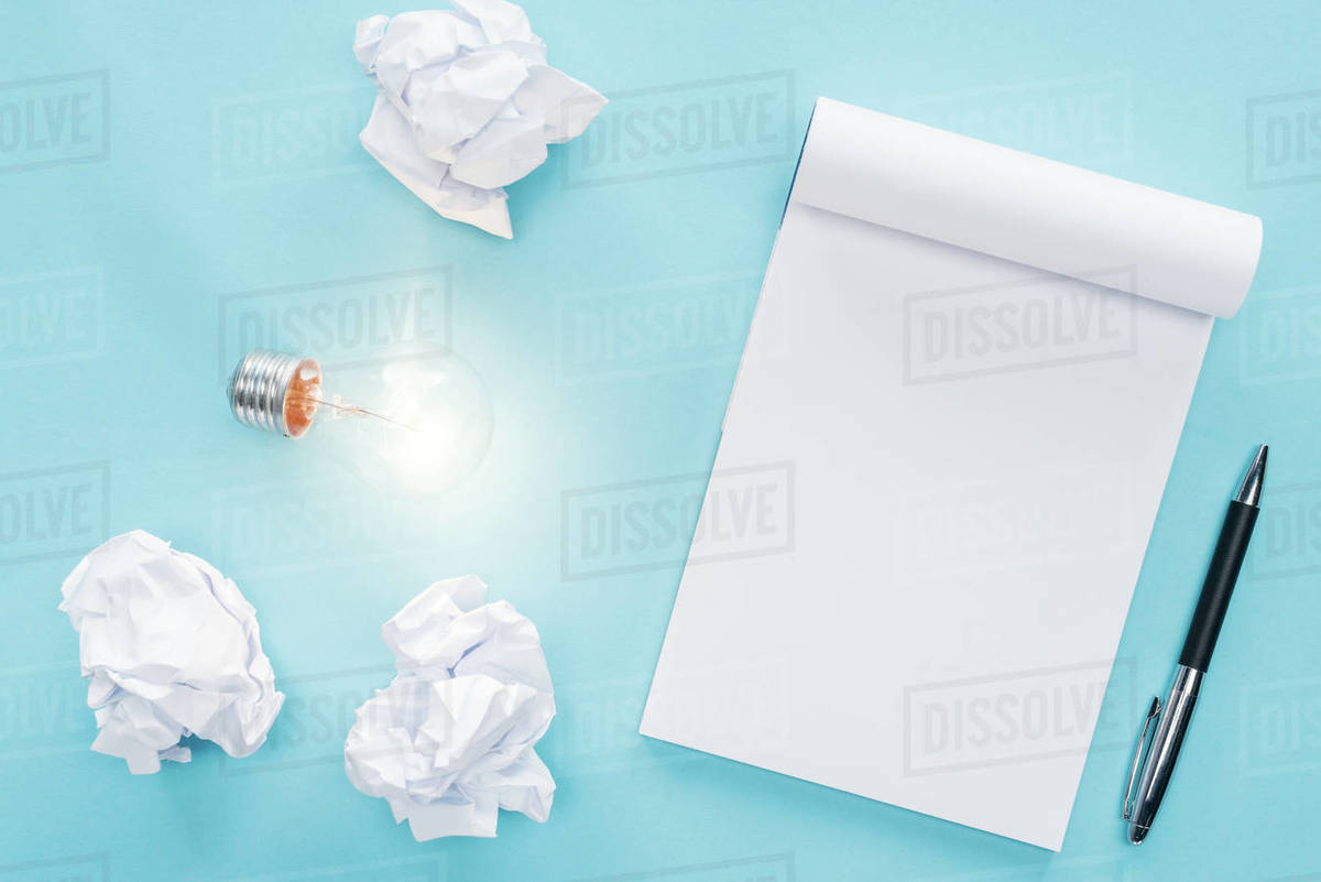 Top view of blank notebook with crumbled paper balls and glowing light ...