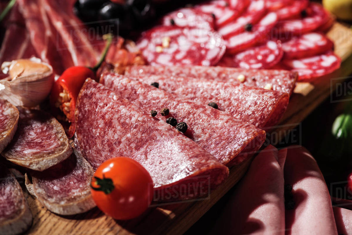 Close up view of sliced salami with tomato, peppercorns and chili on ...