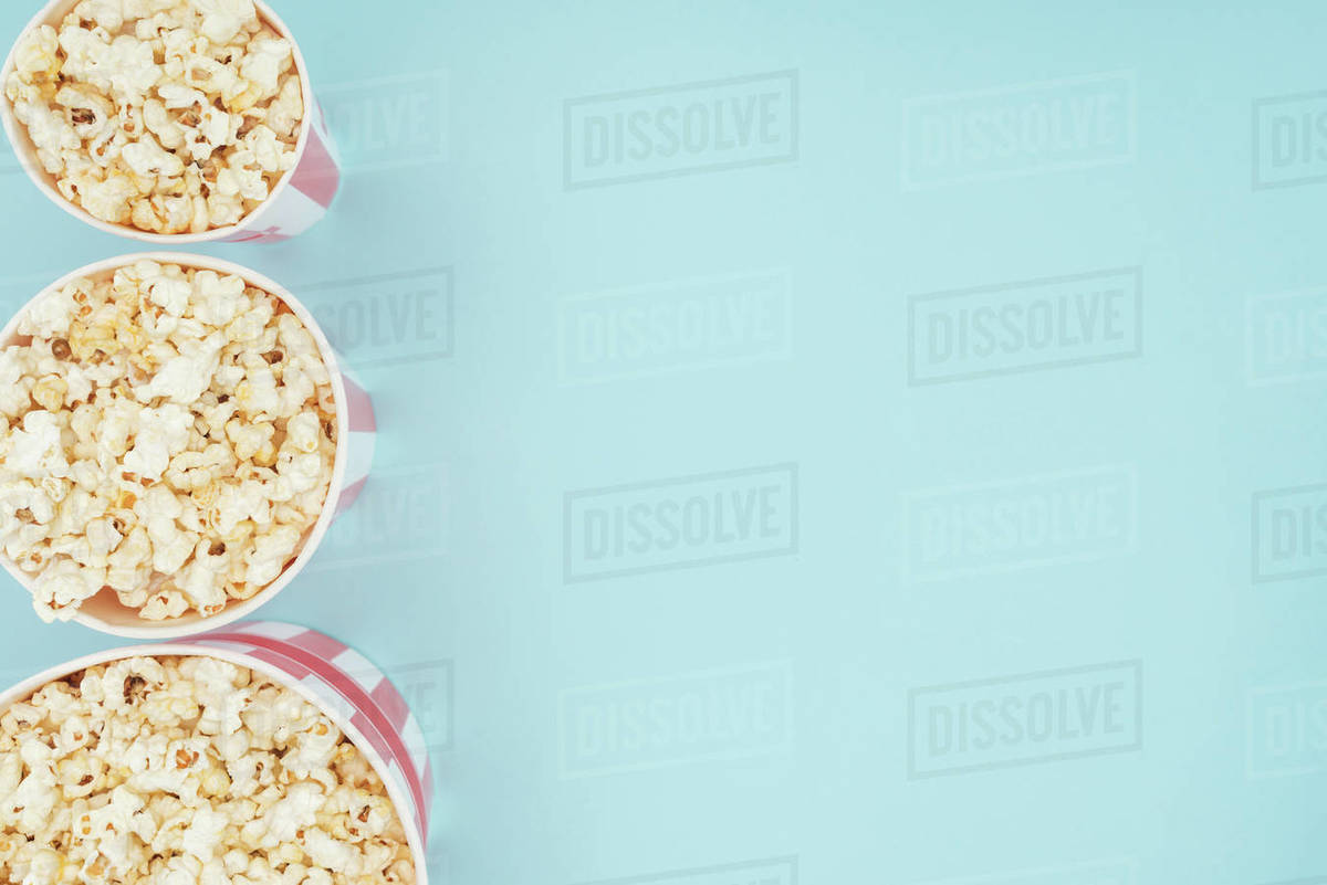 Top view of buckets with popcorn in vertical row isolated on blue ...