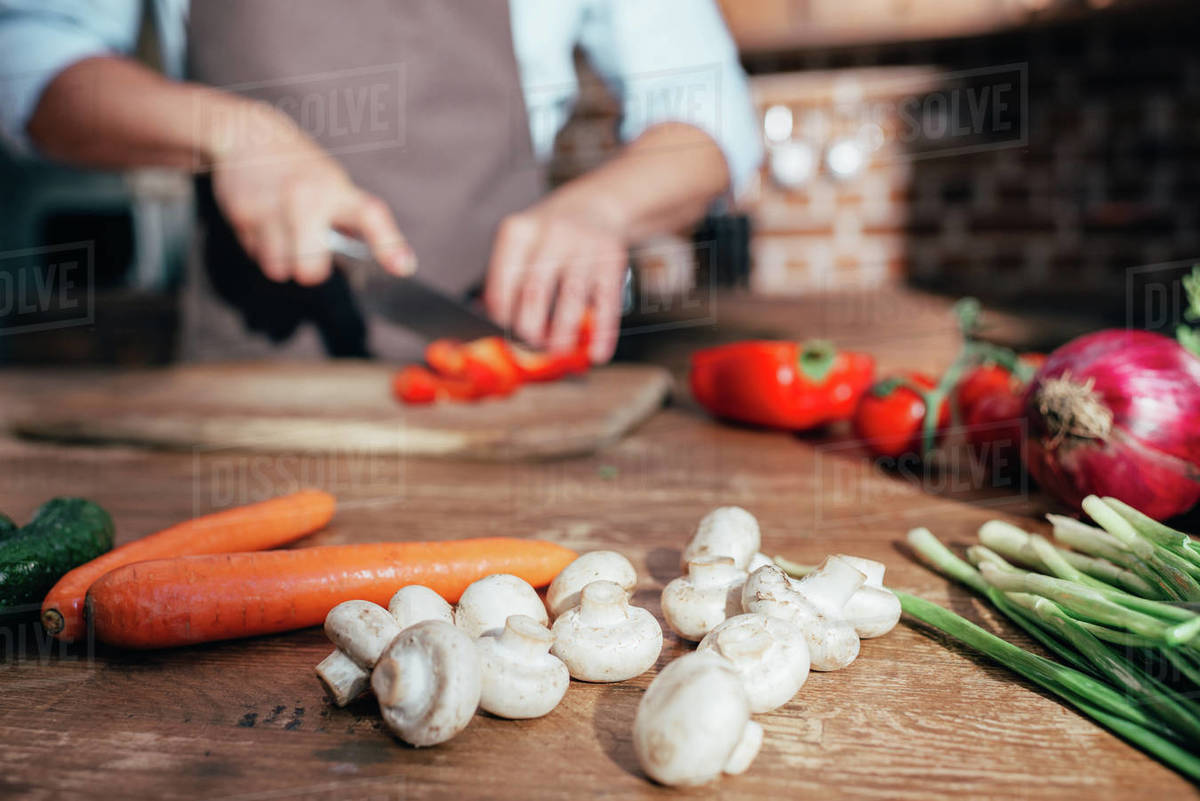 Close-up shot of vegetables on kitchen with man cooking blurred on ...