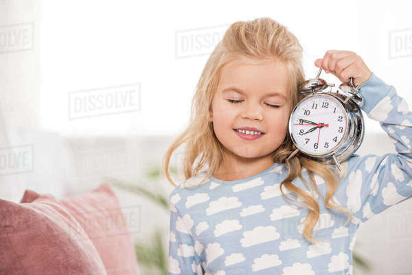 Smiling adorable child with clock and closed eyes in bedroom - Stock ...