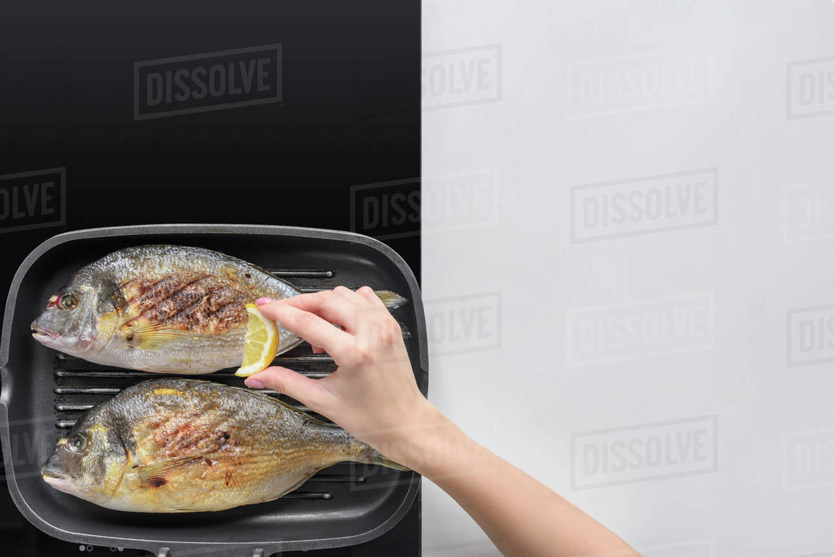 Cropped shot of person squeezing lemon while frying fish - Royalty-free ...