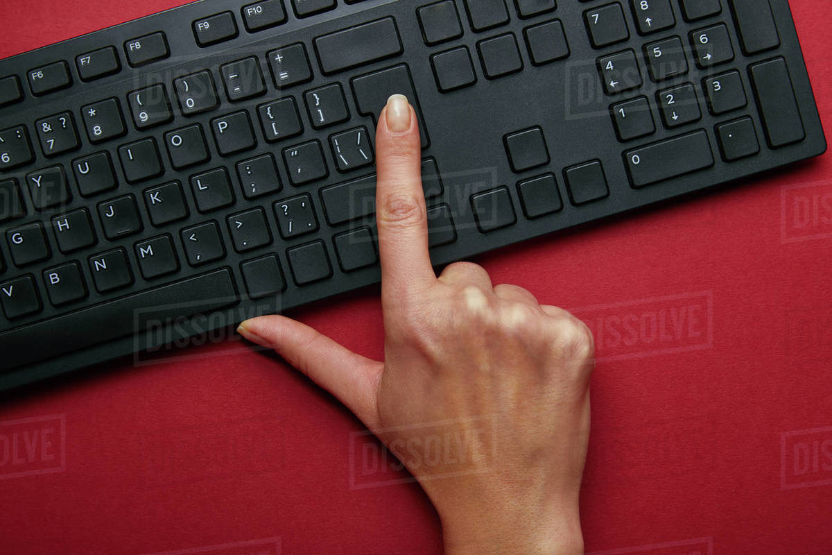 Top view of woman pushing button on black computer keyboard on red ...