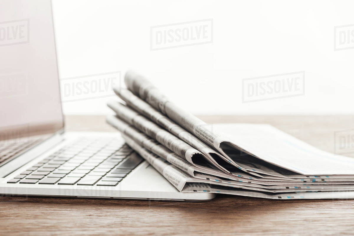 Laptop and stack of newspapers on wooden tabletop - Royalty-free Stock ...