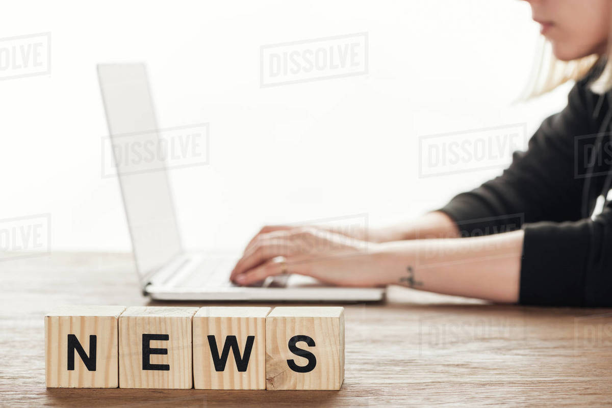 Cropped image of journalist working at laptop, wooden cubes with word ...