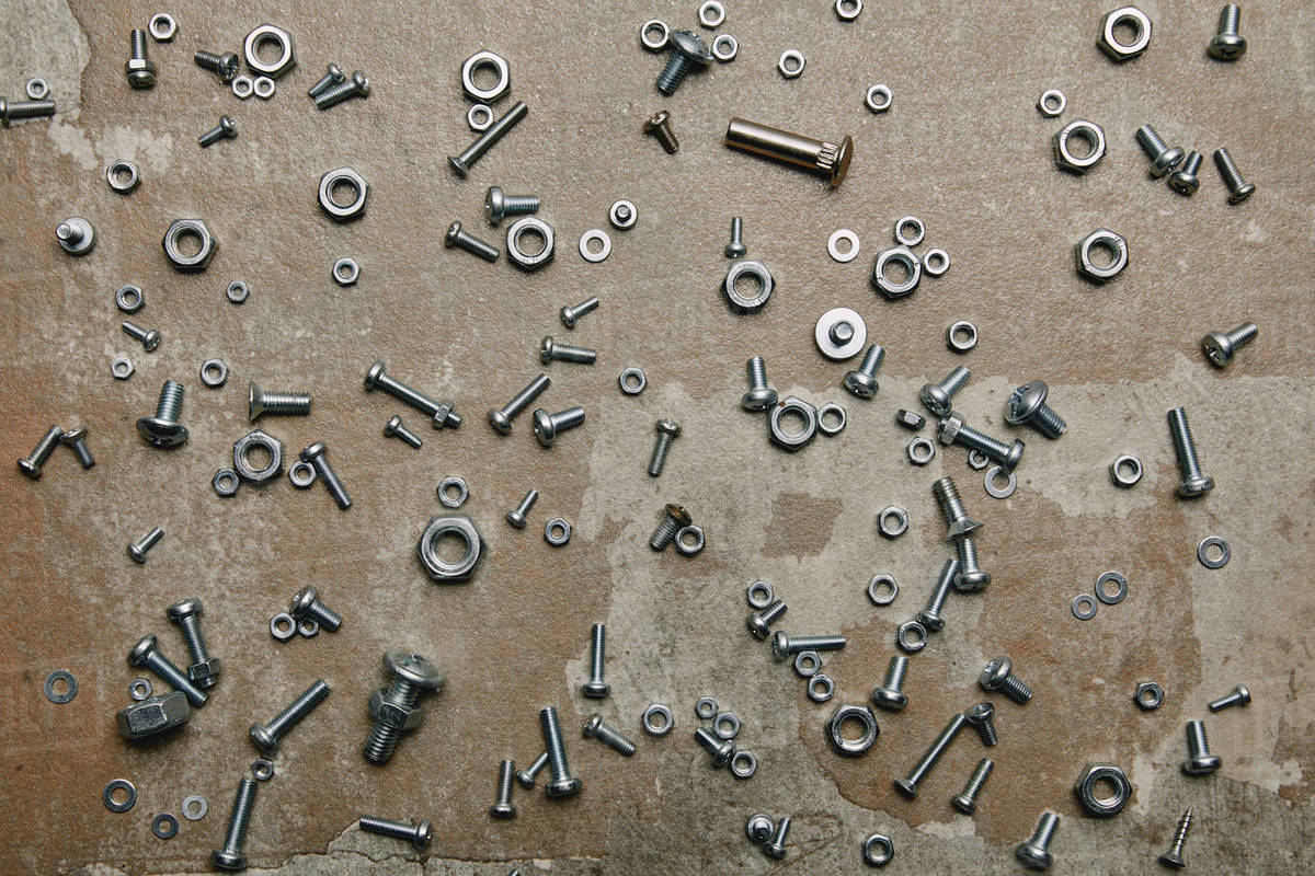Top view of screws and bolts scattered on the background of old surface - Stock Photo - Dissolve