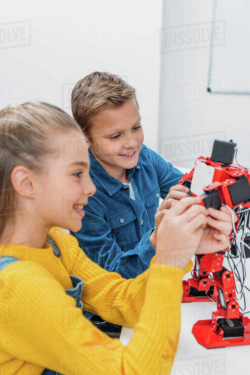 Smiling schoolchildren programming robot together during stem ...