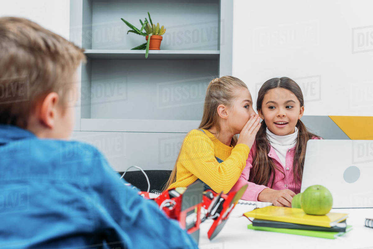 Happy classmates whispering and using laptop after lesson - Stock Photo ...
