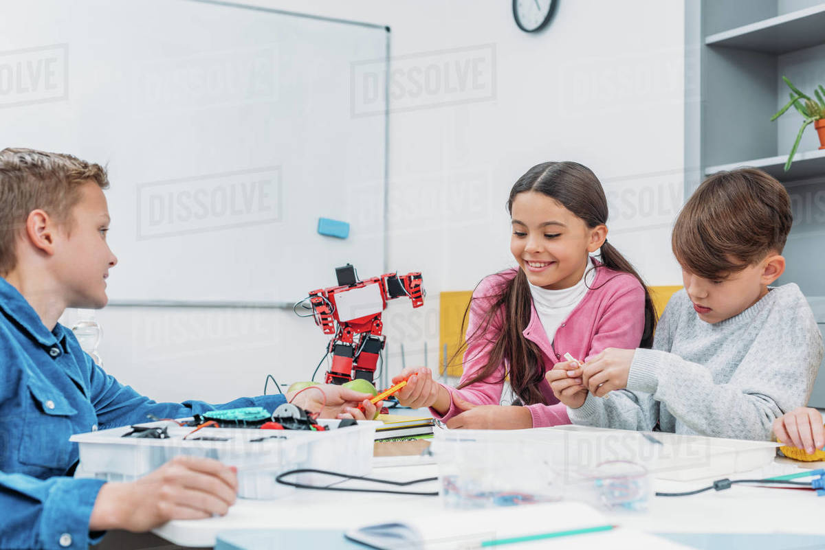 Classmates sitting at table, talking and working together on project ...