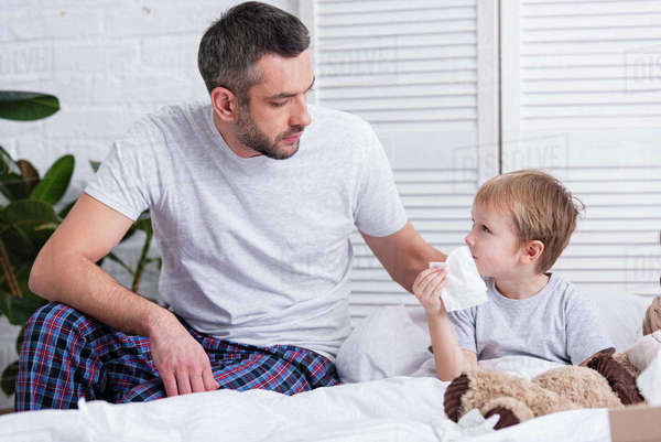 Father taking care of sick son in bedroom - Royalty-free Stock Photo ...