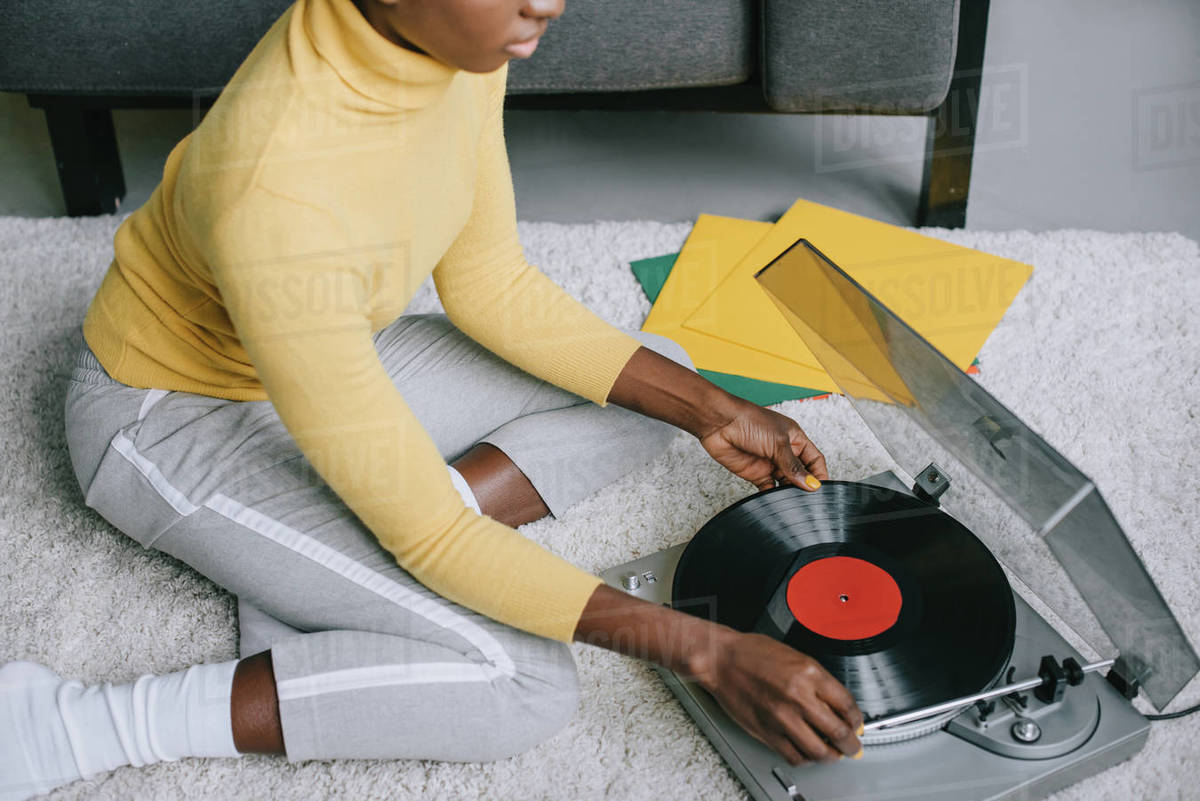 Cropped view of african american woman using record player on carpet ...