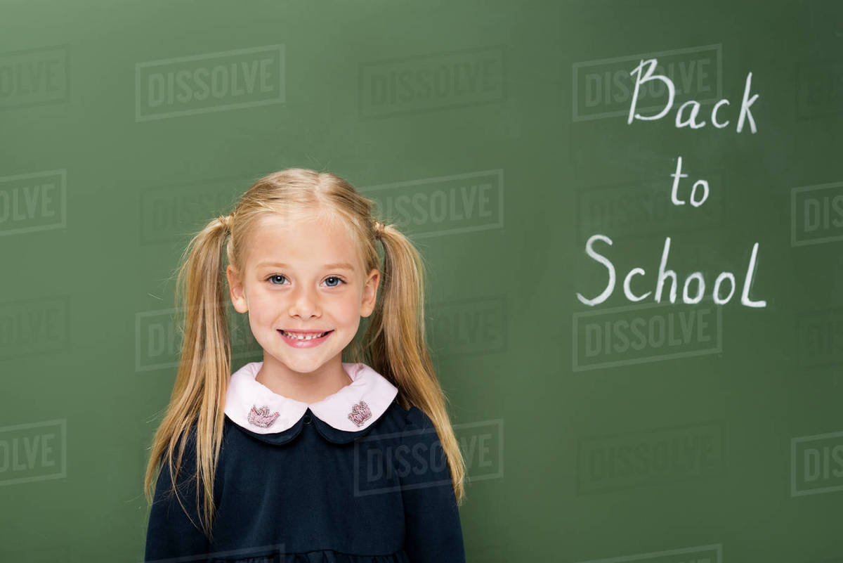 Happy schoolgirl next to chalkboard with back to school sign - Royalty ...