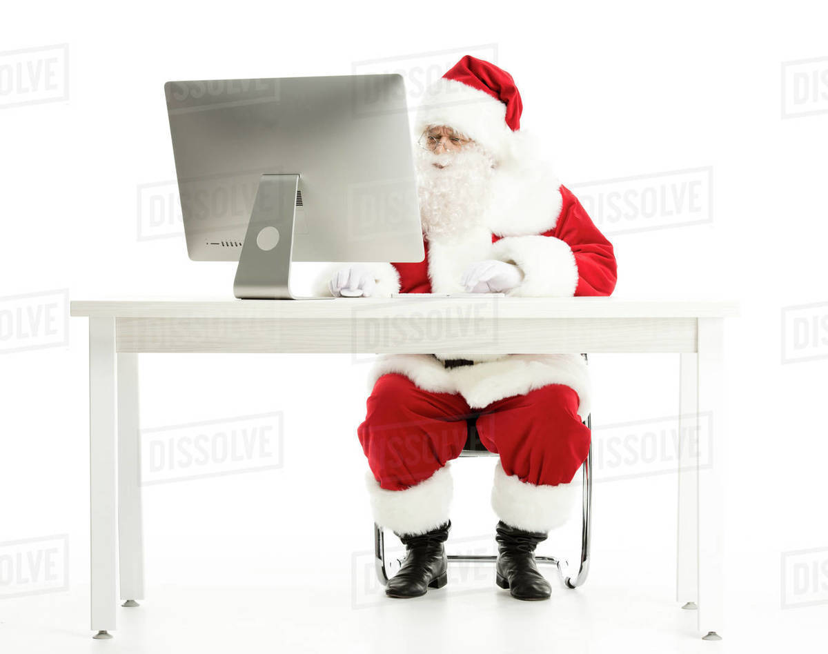 Santa Claus with serious expression looking at computer monitor ...