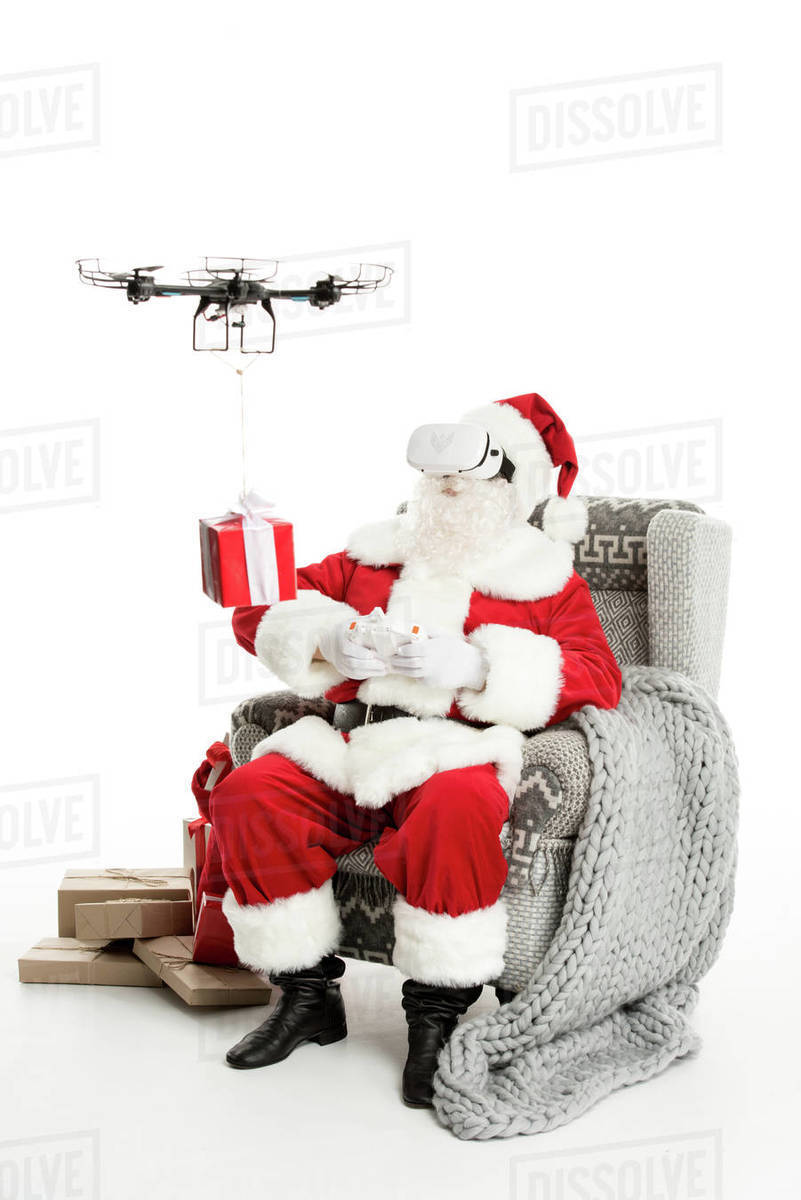Santa Claus, sitting on grey armchair, wearing virtual reality headset ...