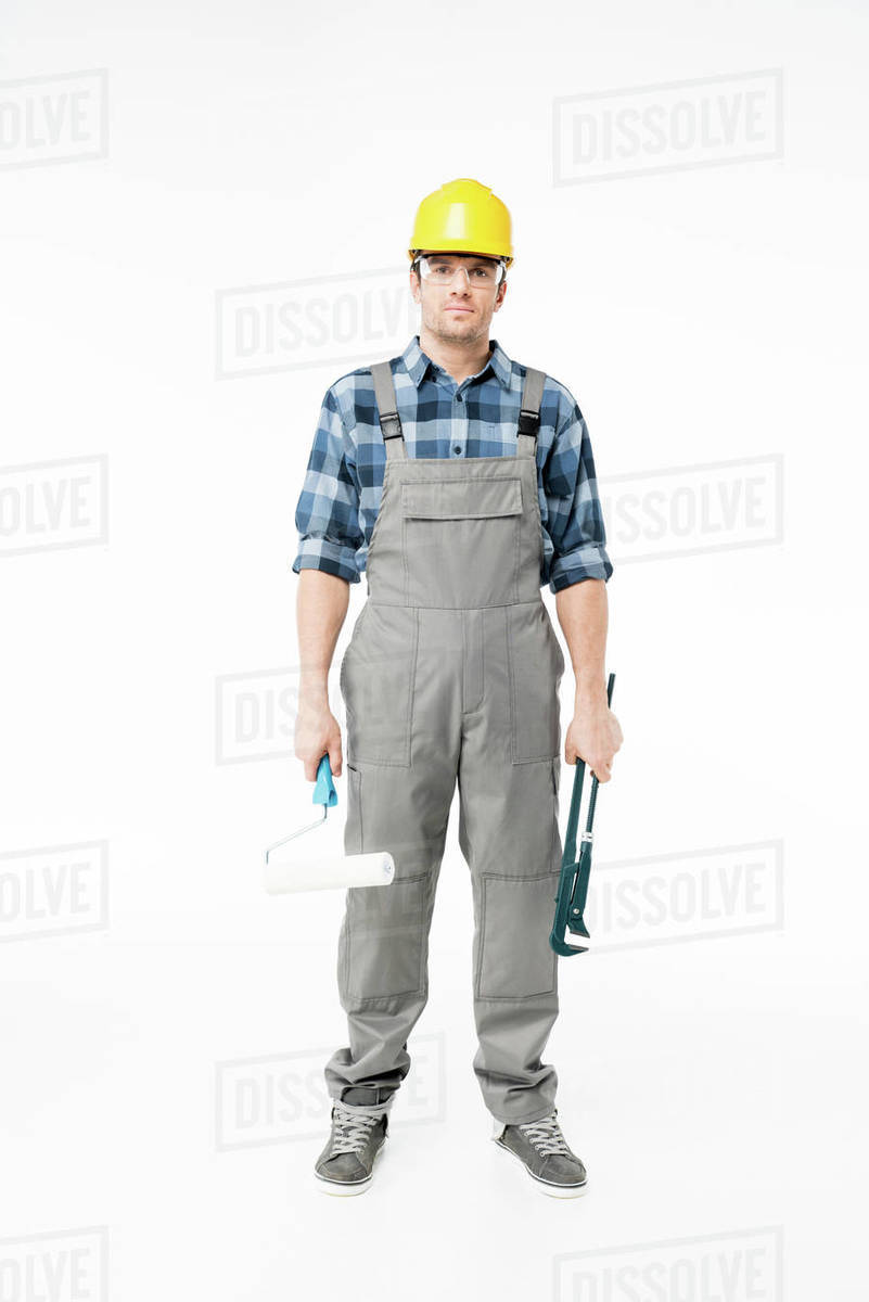 Professional male construction worker holding pipe wrench and paint ...