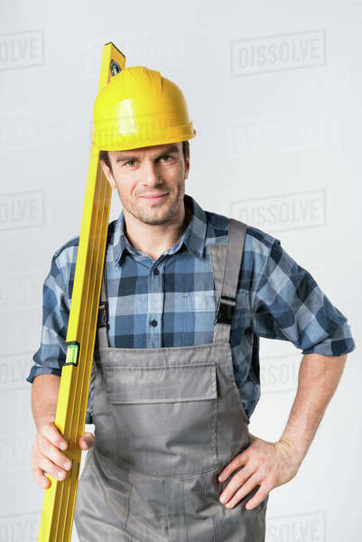 Professional workman with level tool smiling at camera isolated on grey ...