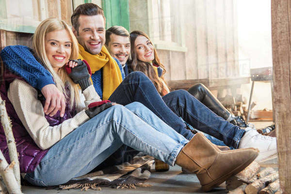Side view of happy friends sitting together and looking to camera ...