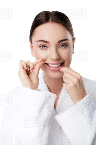 Woman in white bathrobe flossing teeth and looking at camera isolated ...