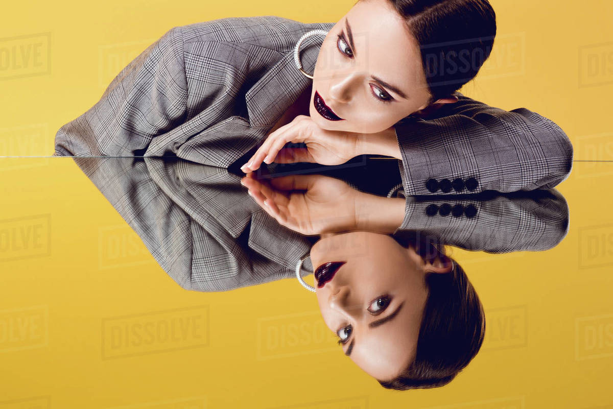 Beautiful glamorous woman in formal wear looking at mirror reflection ...