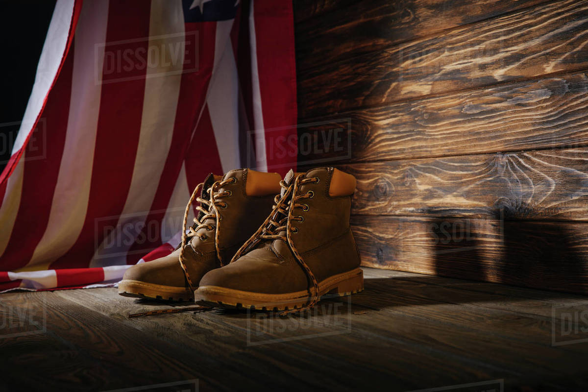 Trekking boots and American flag on wooden surface, travel concept ...