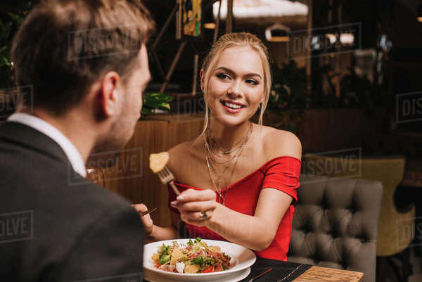 Cheerful girlfriend feeding boyfriend in restaurant - Stock Photo ...