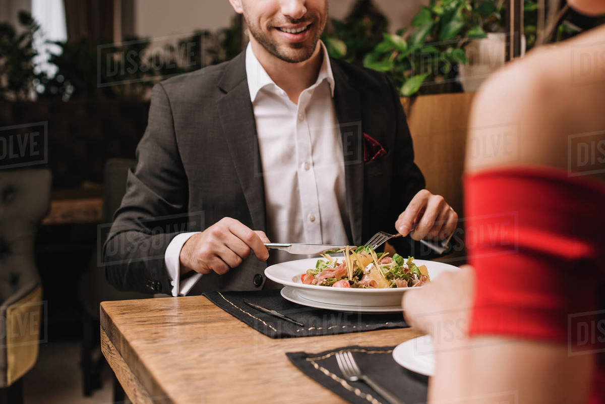 Cropped view of man having dinner with girlfriend in restaurant ...
