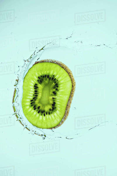 Fresh kiwi slice floating in water with splash on blue - Stock Photo ...