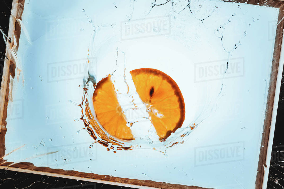 Fresh orange slices floating in water with splash - Stock Photo - Dissolve