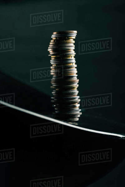 Close up view of stack of different coins standing on edge of table ...