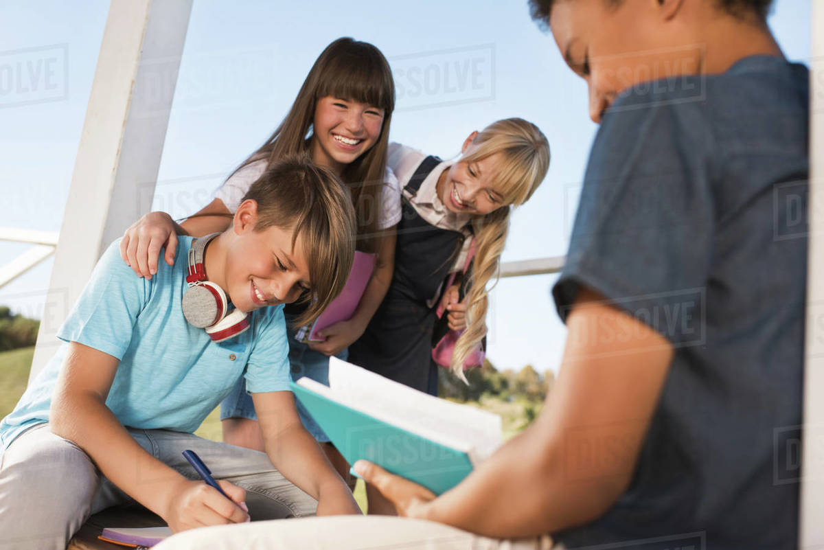 Cute smiling multiethnic teens studying together outdoors - Royalty ...