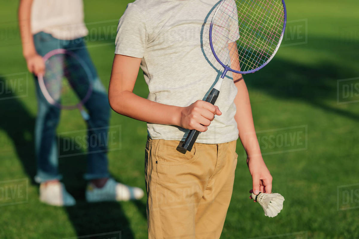 partial view of child holding badminton racket and shuttlecock in hands ...