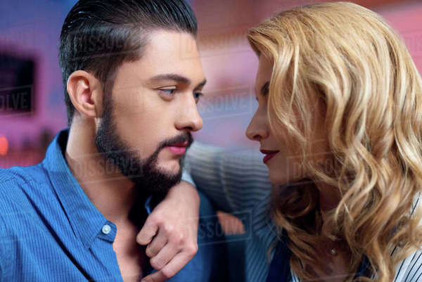 Handsome bearded man and beautiful blonde woman flirting and looking at ...